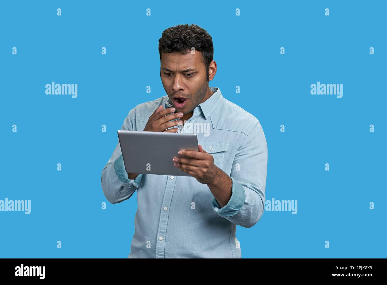 Portrait of shocked indian man looking at tablet pc screen. Isolated on ...