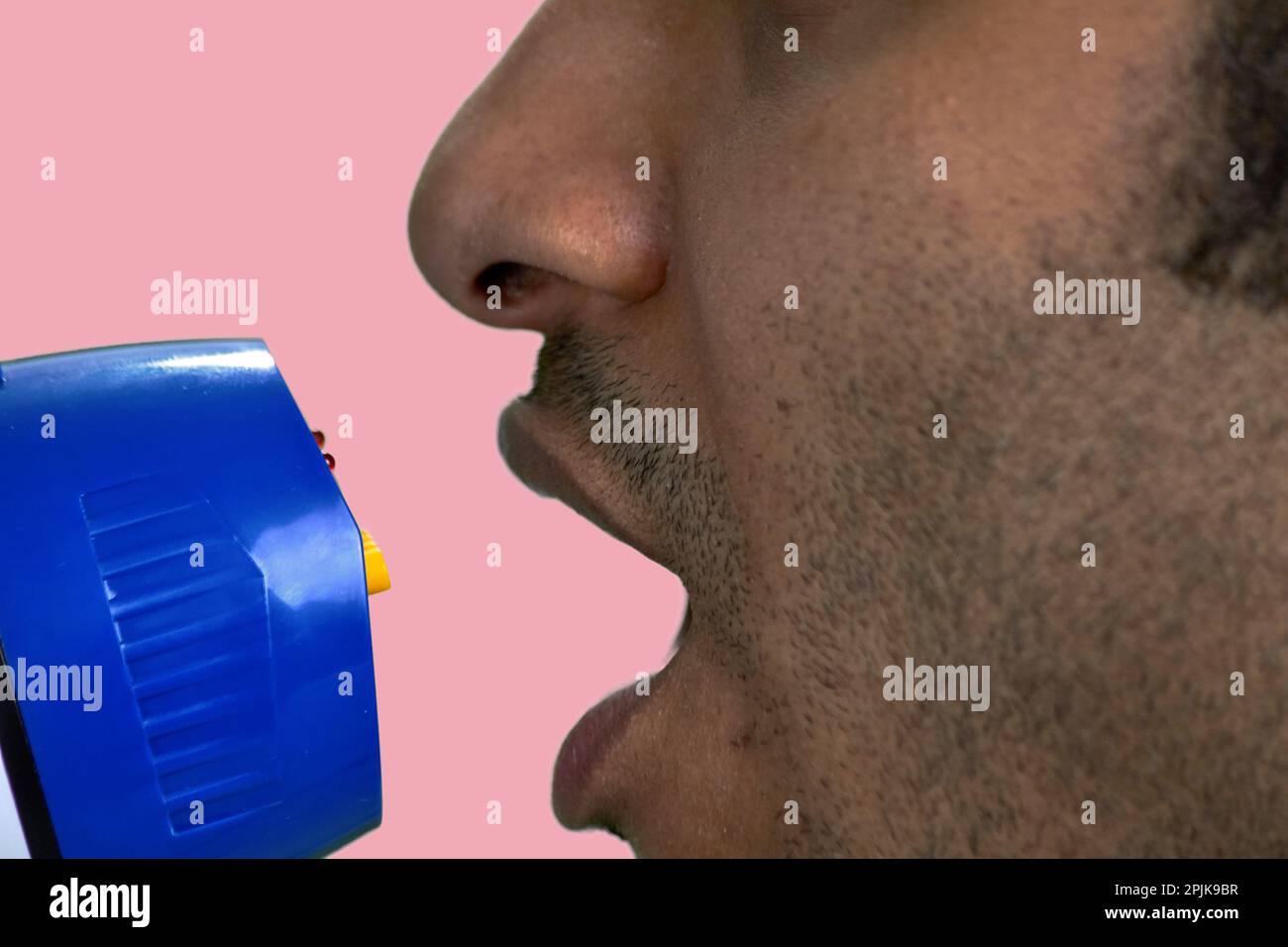 Close up face of indian man speaking in a megaphone. Isolated on pink ...