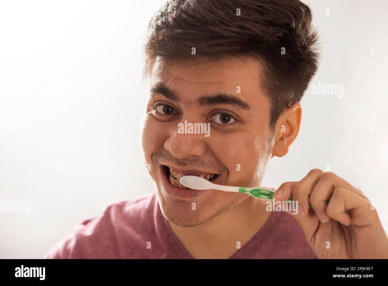 Close-up portrait of a smiling man brushing his teeth Stock Photo - Alamy