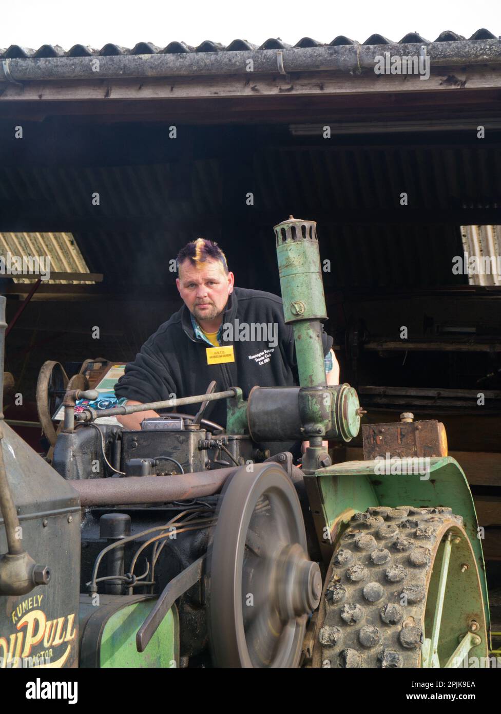 Man driving a vintage tractor at the Museum of Rural Life, Lamport Hall, Northamptonshire, UK ...