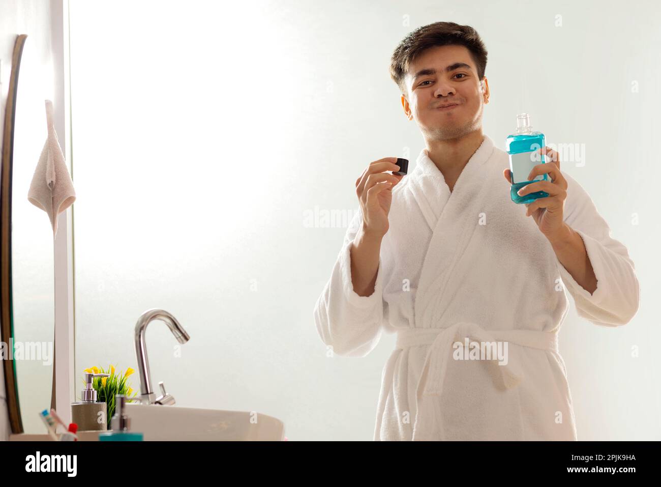 Young man rinsing mouth with mouthwash in bathroom Stock Photo - Alamy
