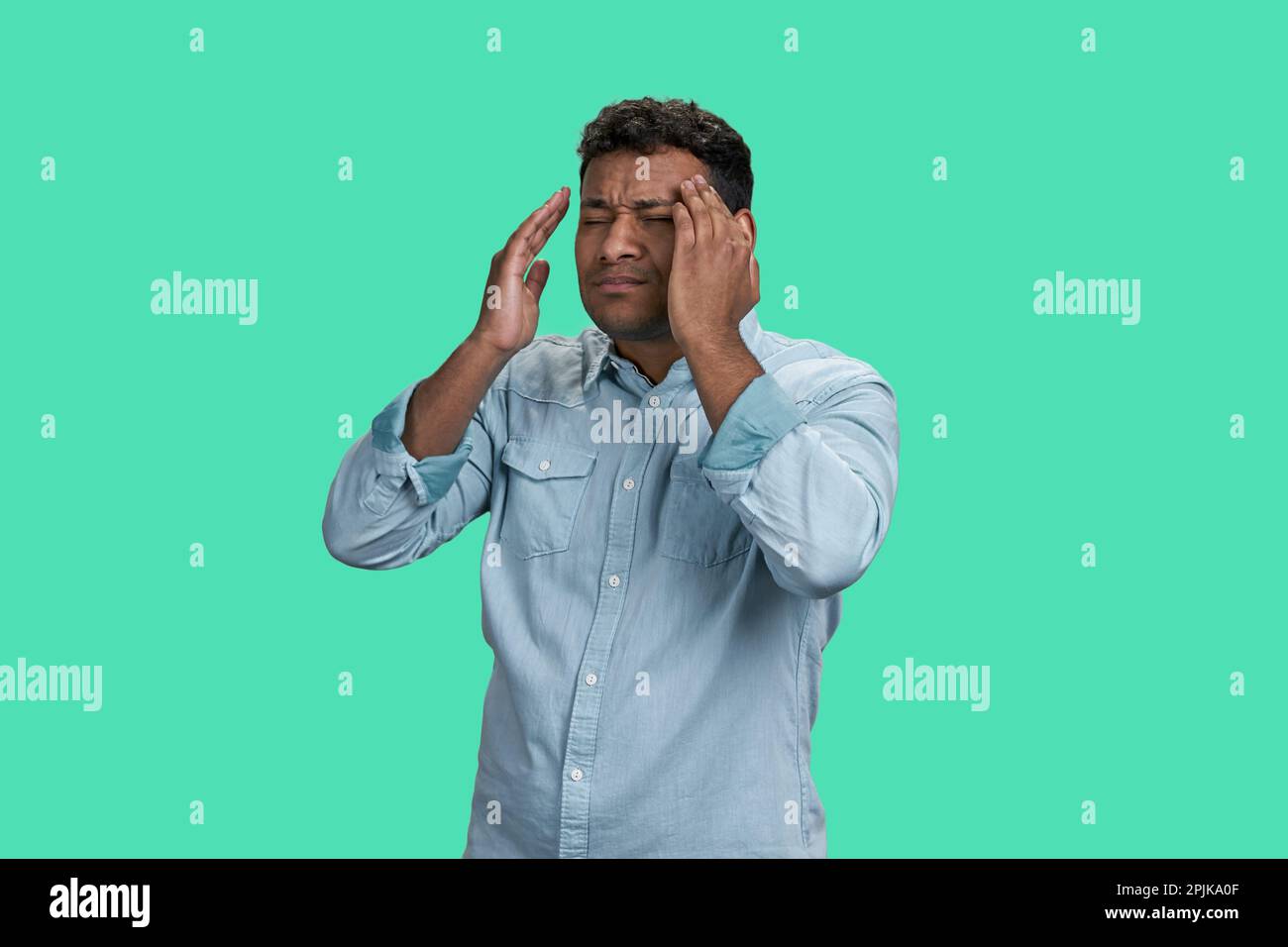 Young indian man having headache or migraine pain. Isolated on green ...