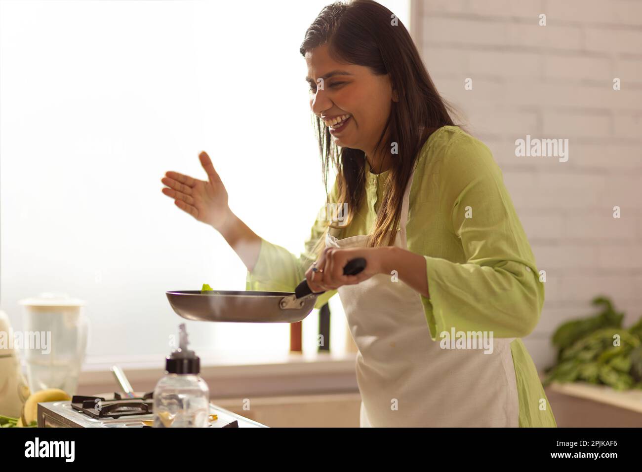 Woman smelling food while cooking in kitchen Stock Photo - Alamy
