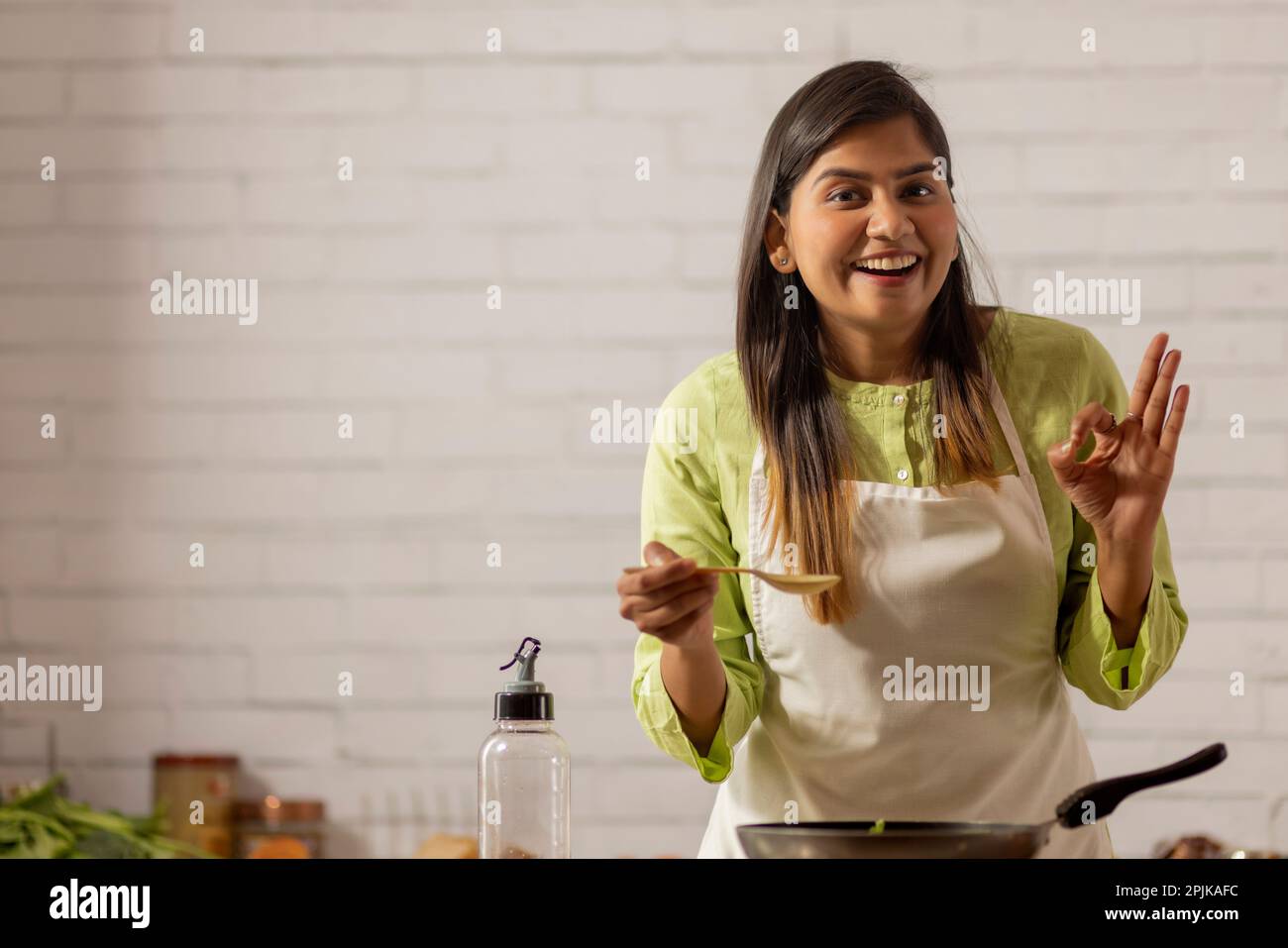 Portrait of cheerful woman cooking in kitchen Stock Photo - Alamy