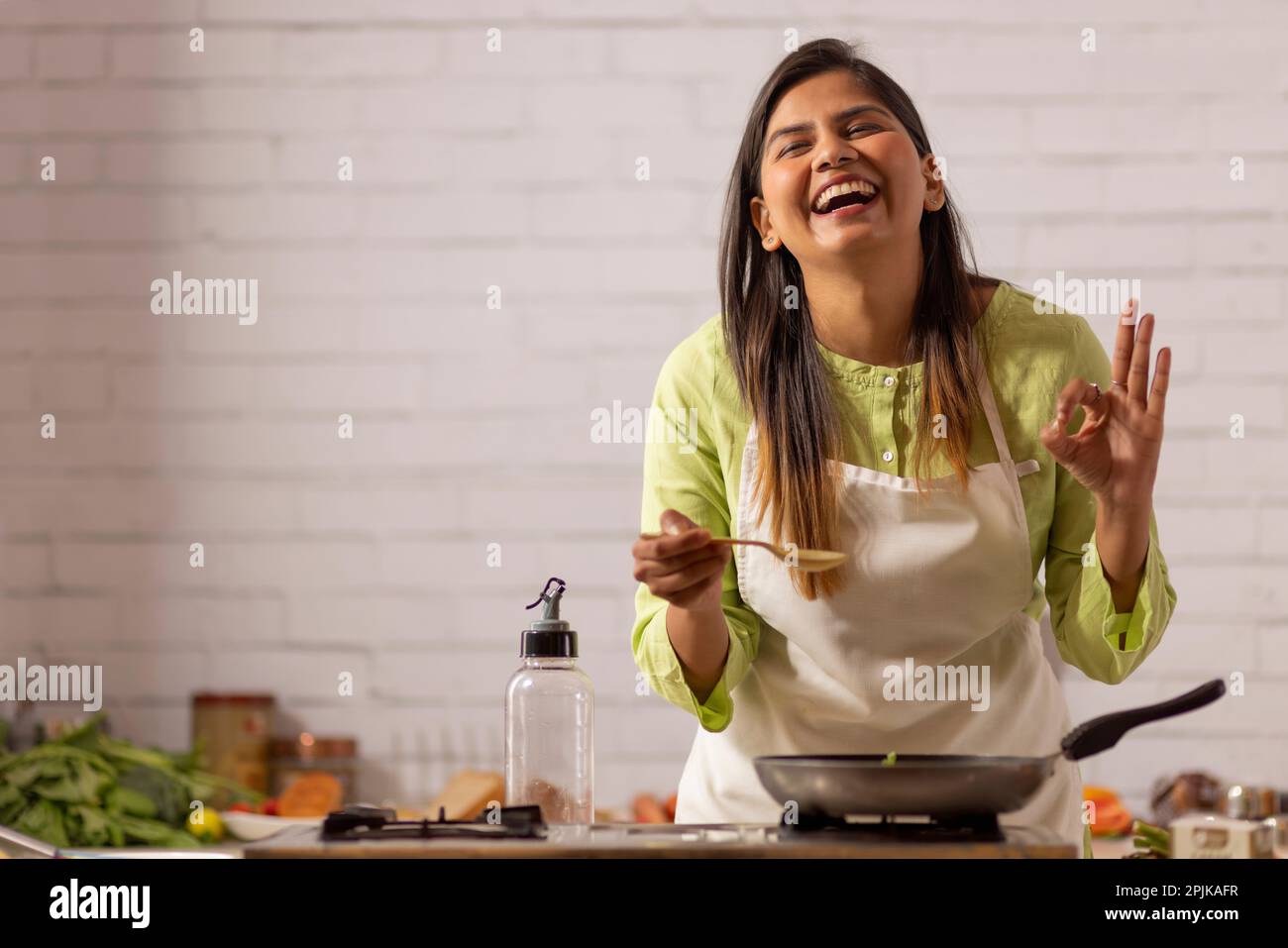 Portrait of cheerful woman cooking in kitchen Stock Photo - Alamy