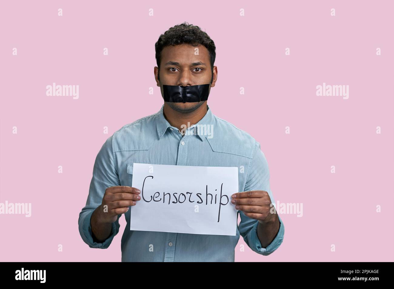 Indian guy silenced with mouth taped holding paper sheet with ...