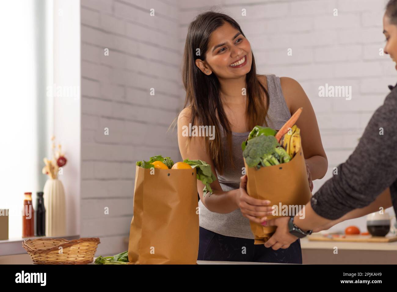 Woman receiving bags of vegetables from delivery person Stock Photo - Alamy
