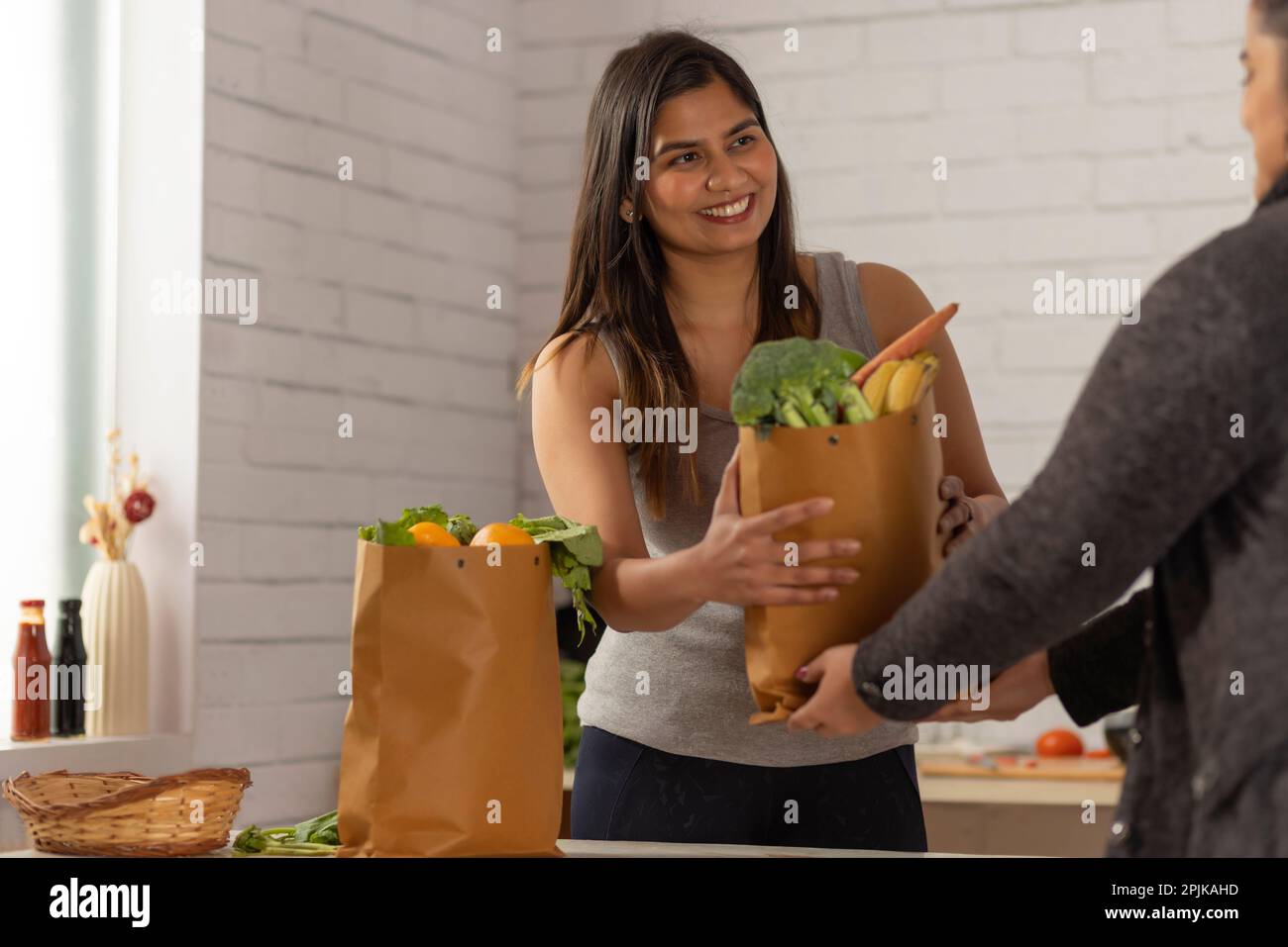 Woman receiving bags of vegetables from delivery person Stock Photo - Alamy