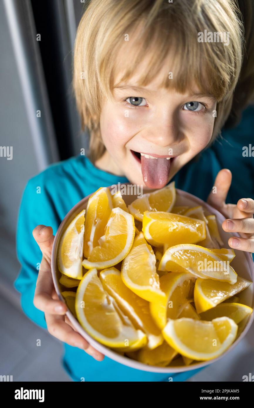 child holds plate with sliced pieces of ripe lemon in hands, cheerfully ...