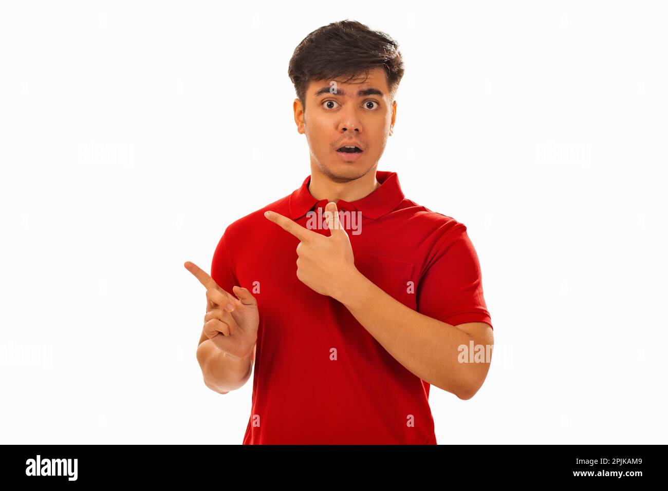 Surprised young man pointing against white background Stock Photo - Alamy