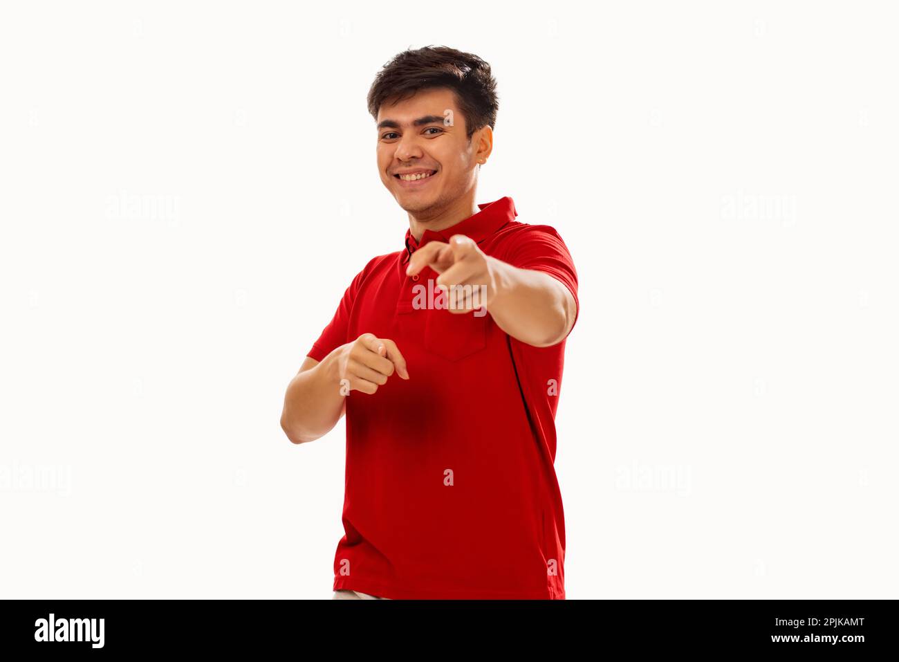 Portrait of young man pointing towards camera against white background ...