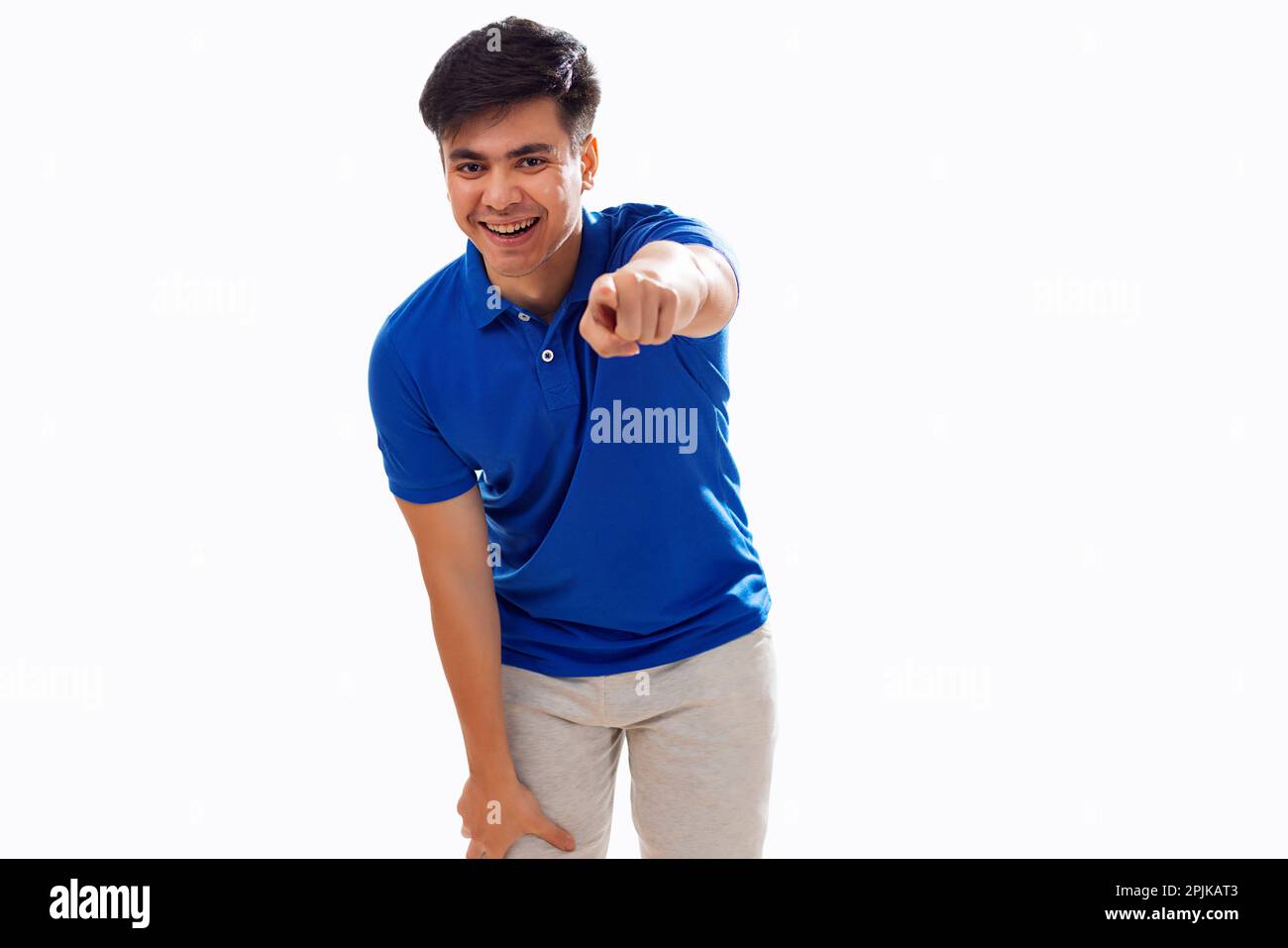 Portrait of young man pointing towards camera against white background ...