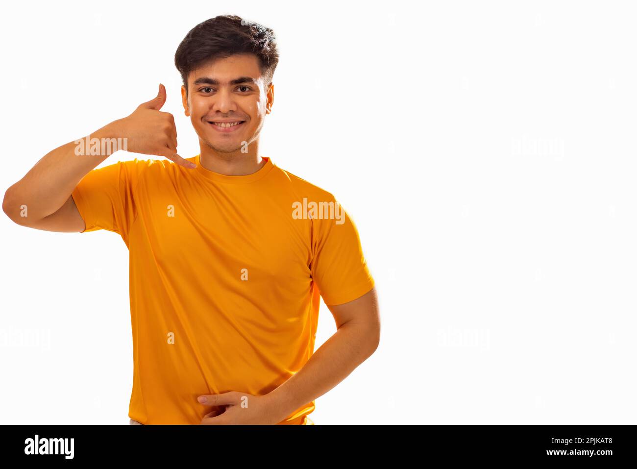 Portrait of young man showing calling gesture against white background ...