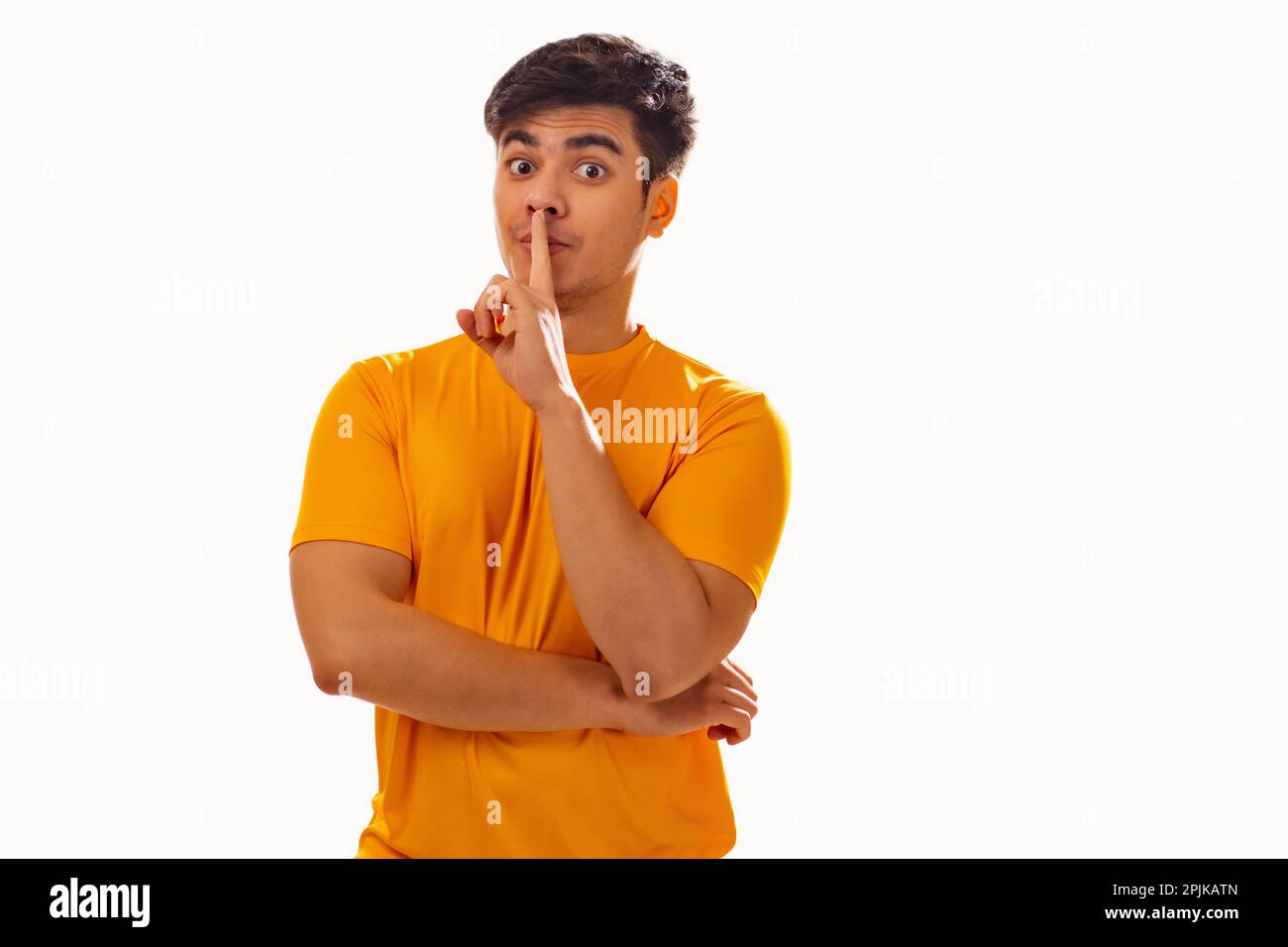 Portrait of young man showing hush gesture against white background ...