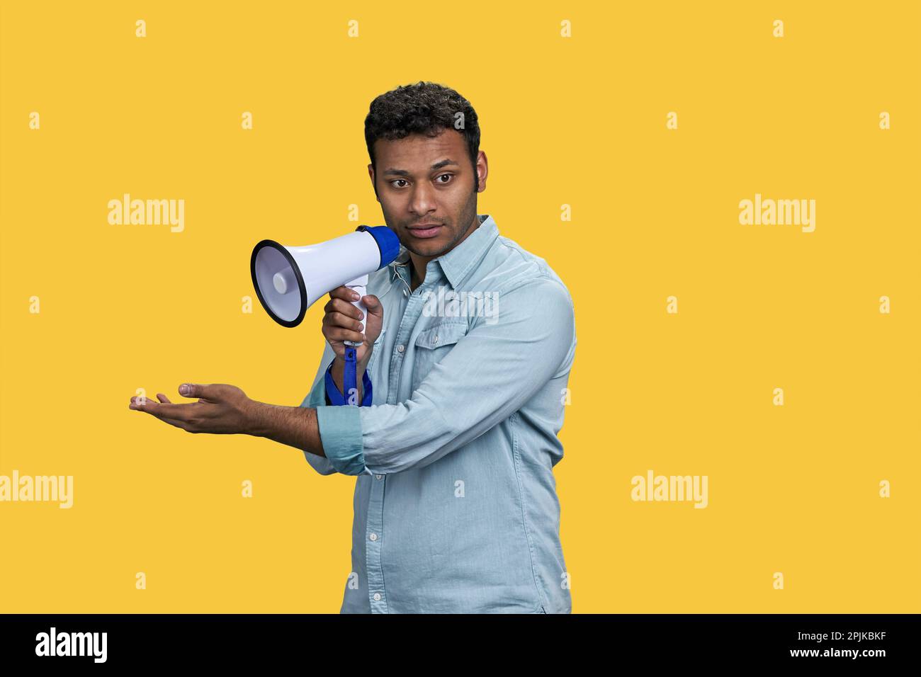 Young indian man speaking in megaphone and showing something with his ...