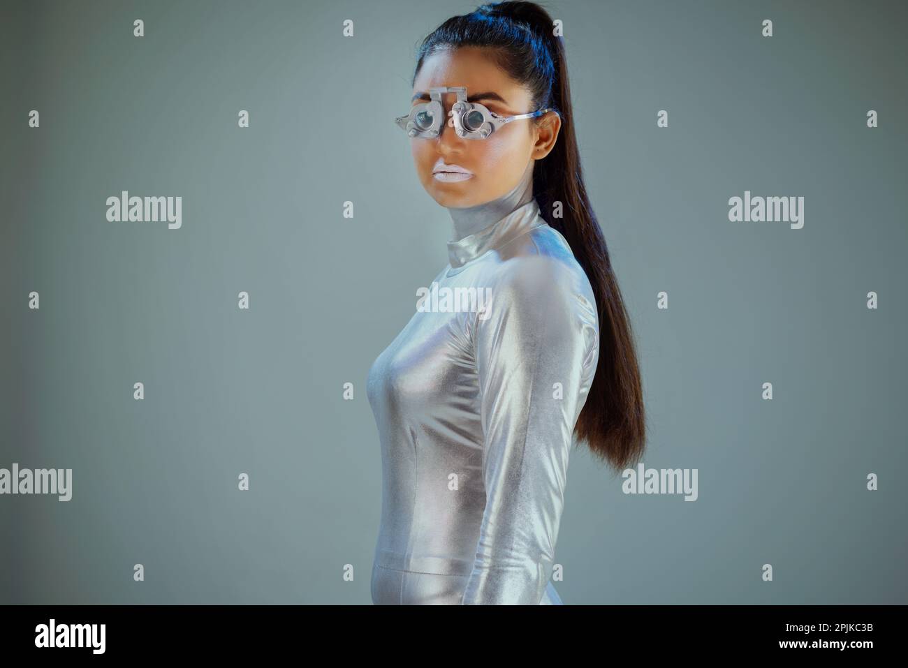 Side view of silver robot with eye prosthesis looking at camera on grey ...