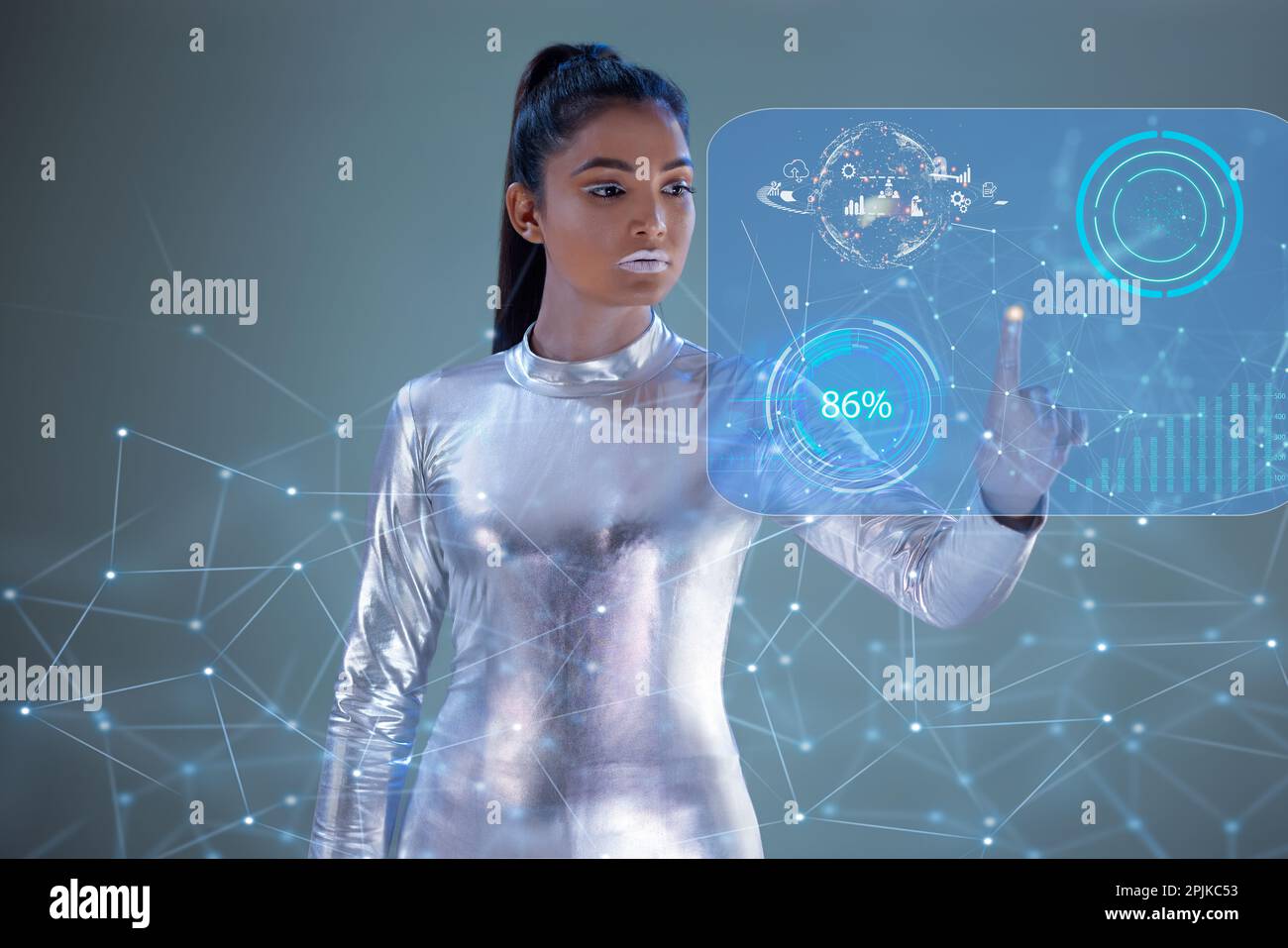 A woman wearing silver dress touching a digital Screen standing on a ...