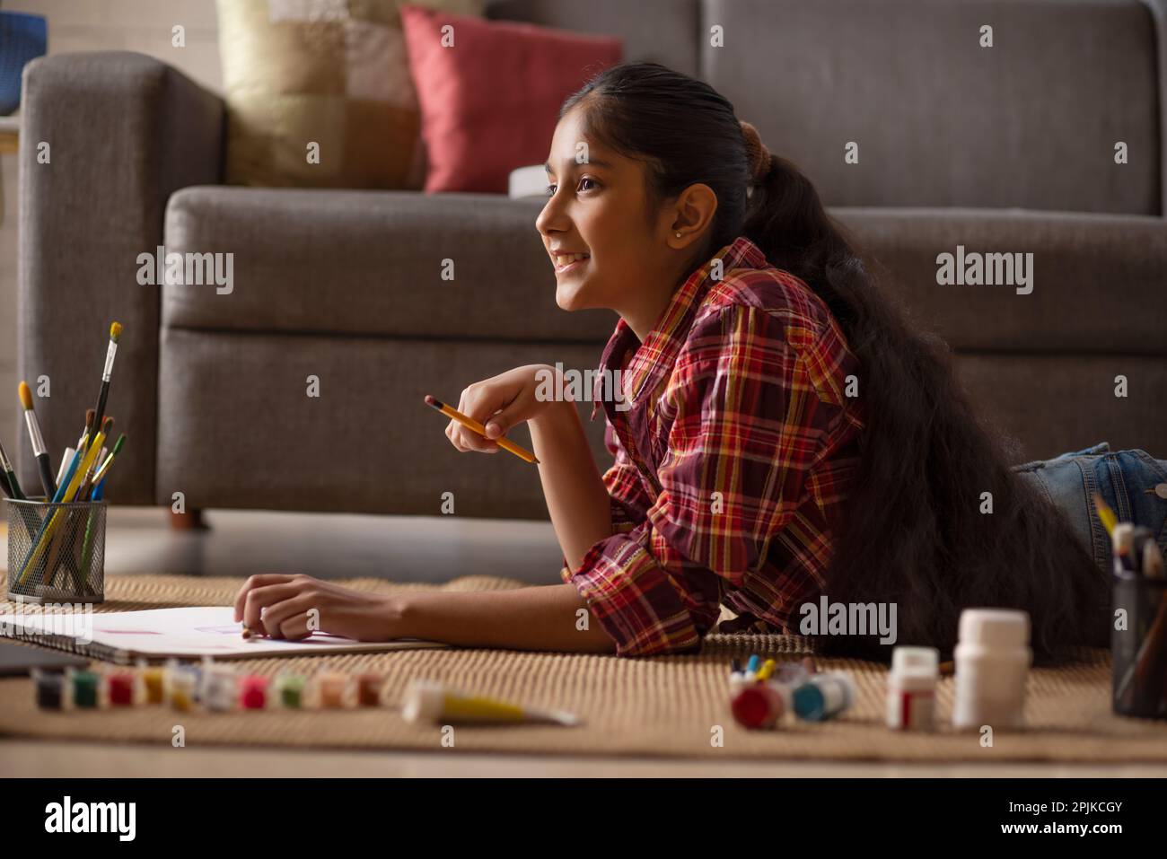 Girl drawing while lying down on carpet in living room Stock Photo - Alamy