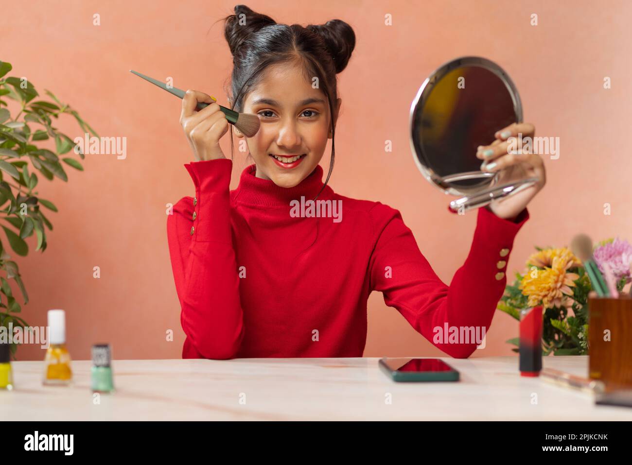 Portrait of a tween girl applying make-up on her cheek Stock Photo - Alamy