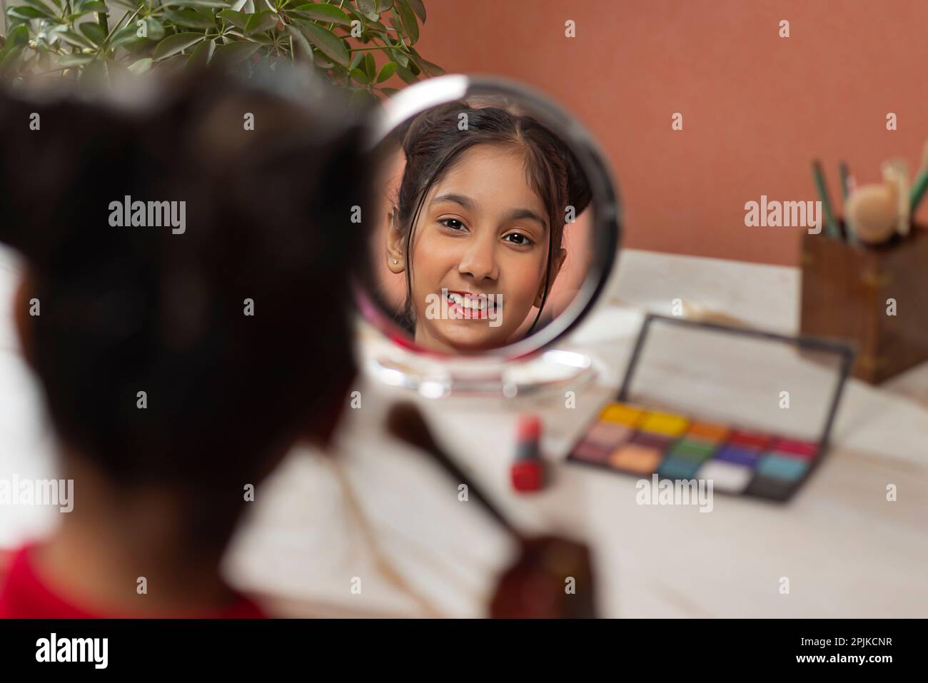 Tween girl looking herself in vanity mirror during make-up Stock Photo ...
