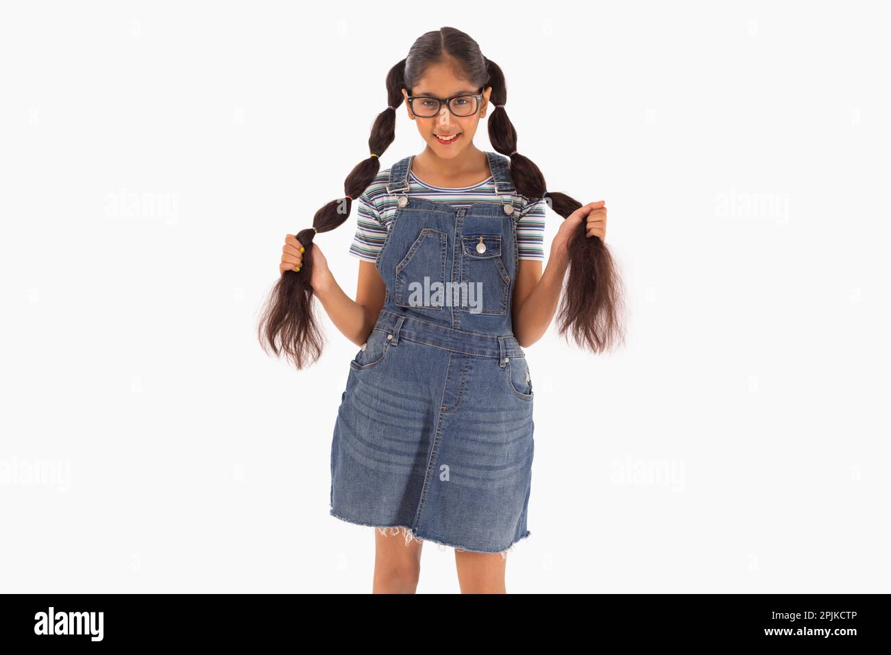 Tween girl with spectacles holding her braided hair against white ...