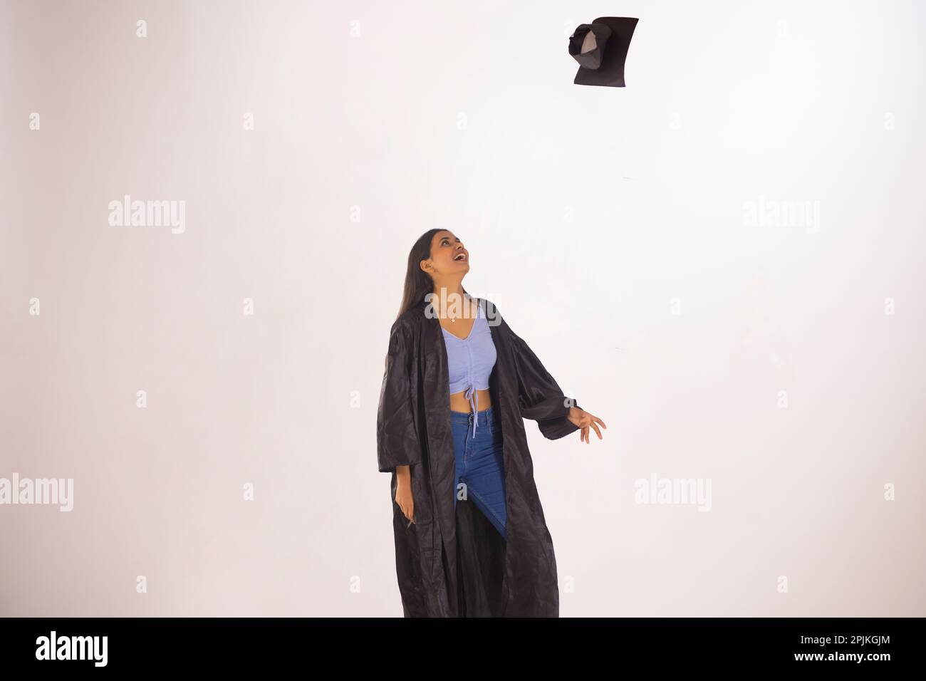 Portrait of young woman throwing her mortar board in the air against ...