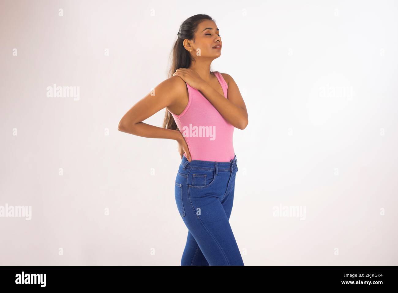 Portrait of a woman suffering from shoulder and back pain against white ...