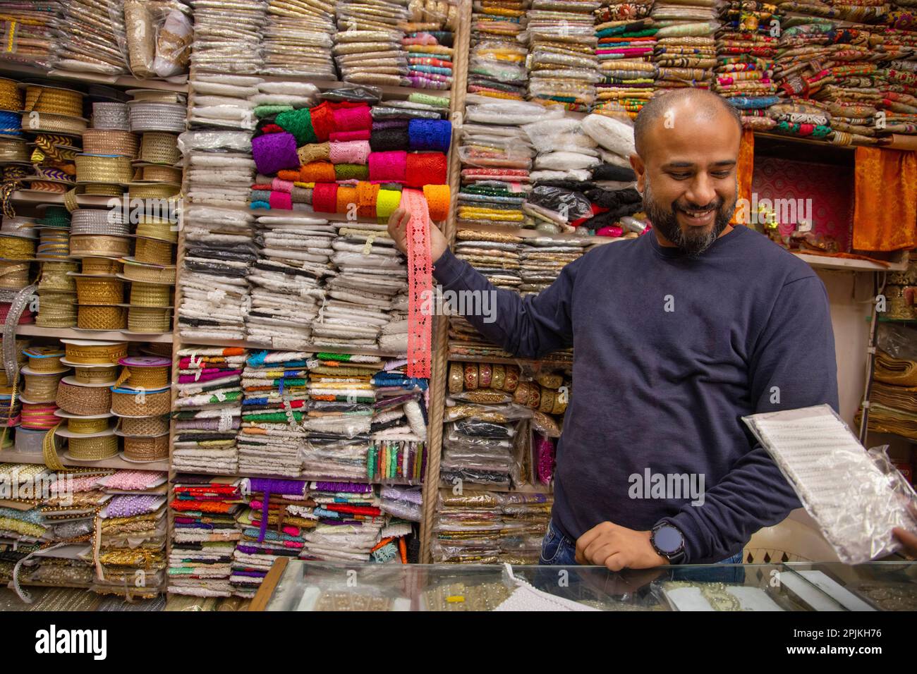 Male fabric vendor showing border and lace to a buyer Stock Photo - Alamy