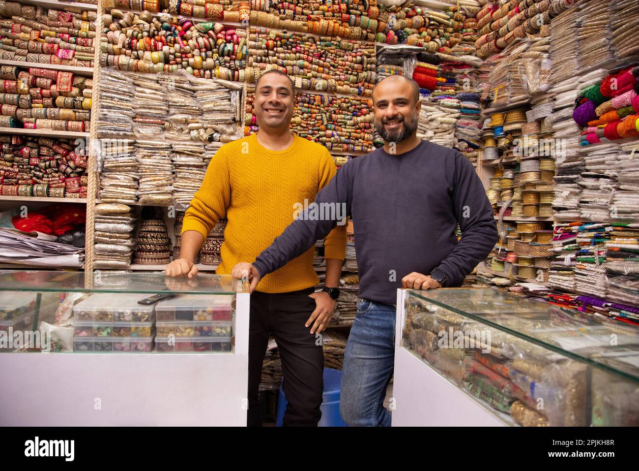 Portrait of two cheerful male shop keepers standing at his lace shop ...