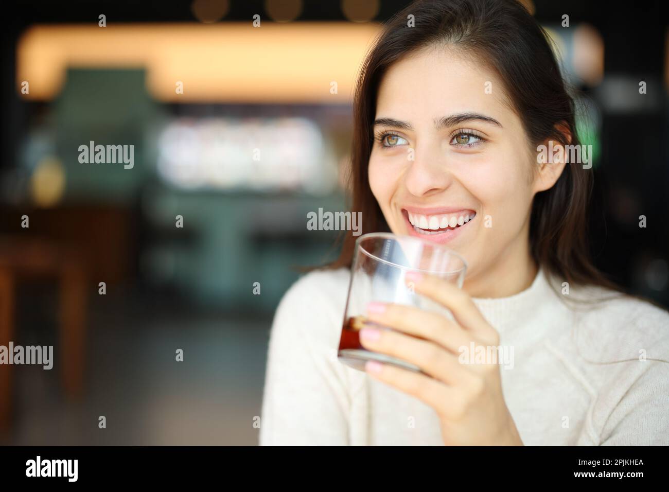 Happy woman drinking soda in a restaurant looking away in a restaurant ...