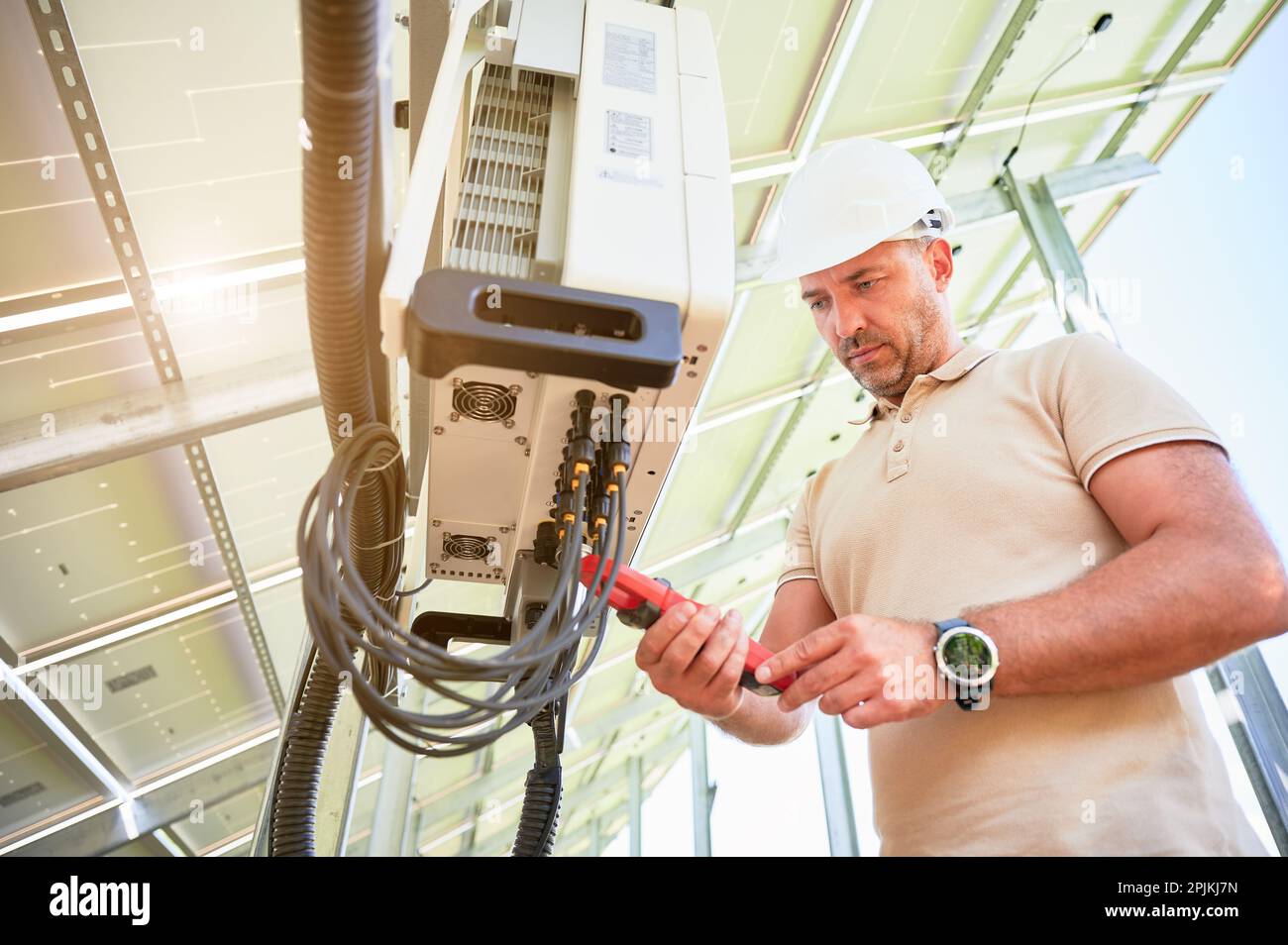 Bottom view of worker checking solar inverter work. Measuring output ...