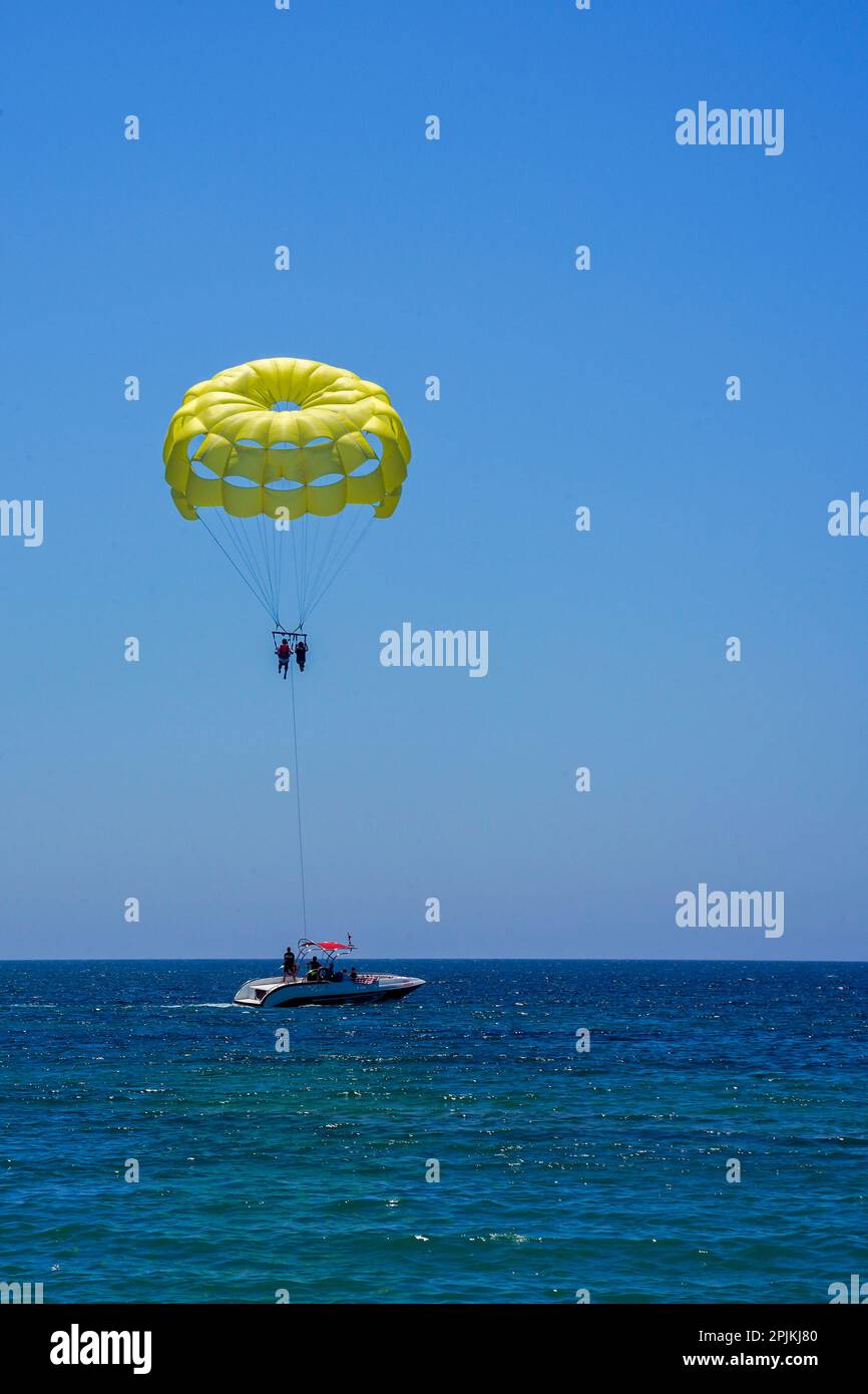 Parasailing on a yellow parachute against the blue sky. Beach extreme ...