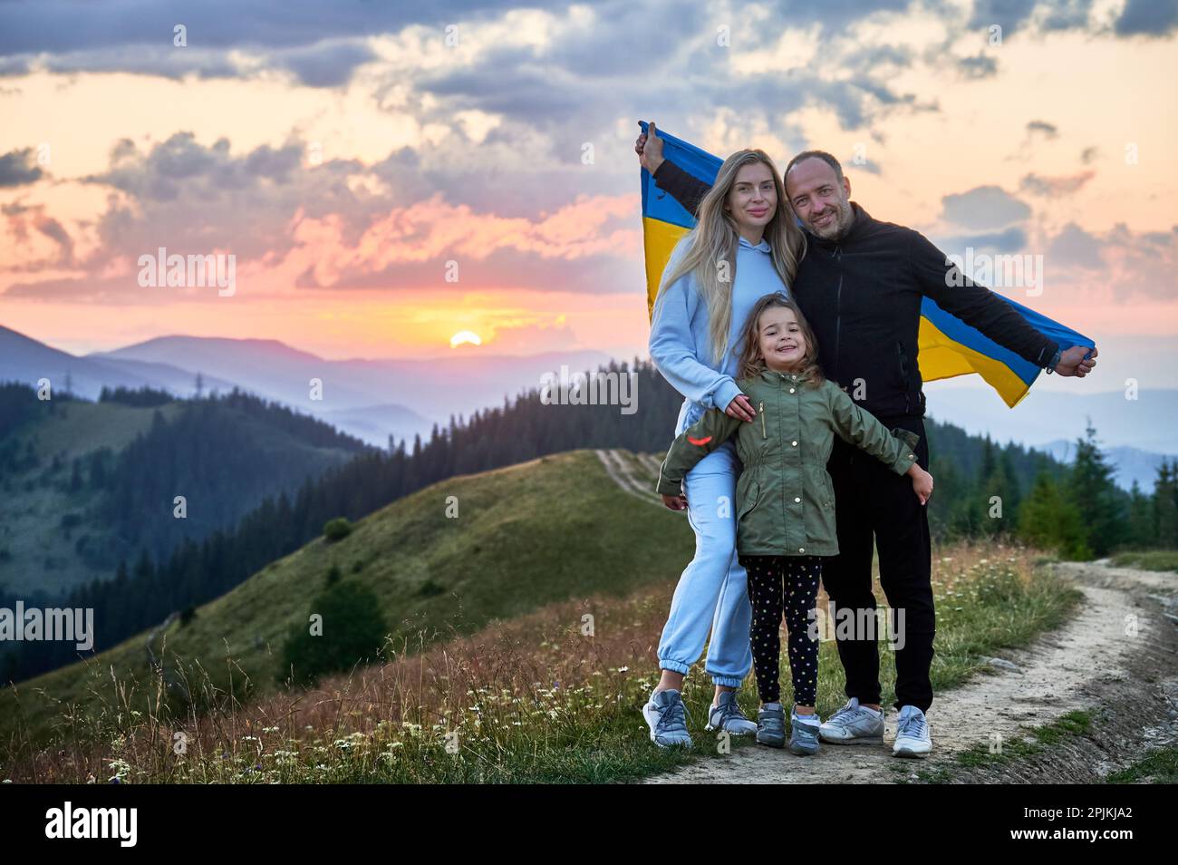 Happy family of hikers waving Ukrainian flag. Man with his wife and ...