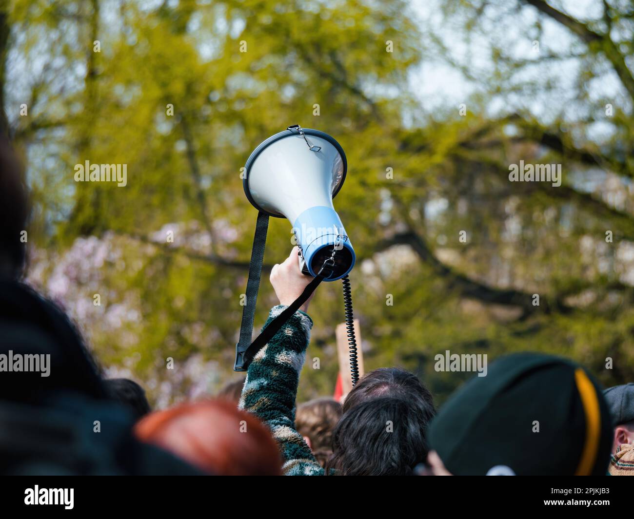 A large crowd of protesters hold up signs and banners, shouting their ...
