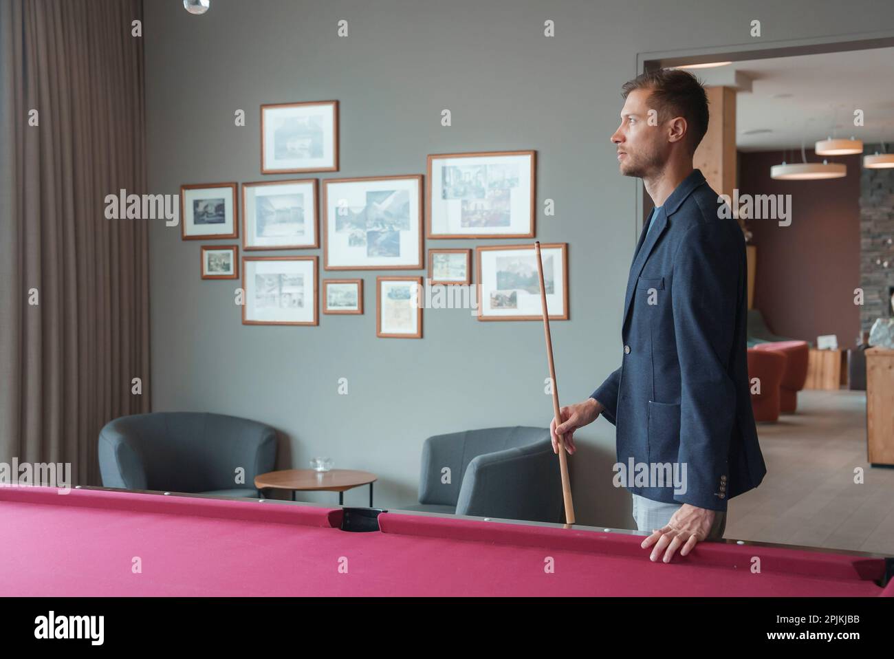 Thoughtful man holding snooker stick standing in luxury hotel Stock ...