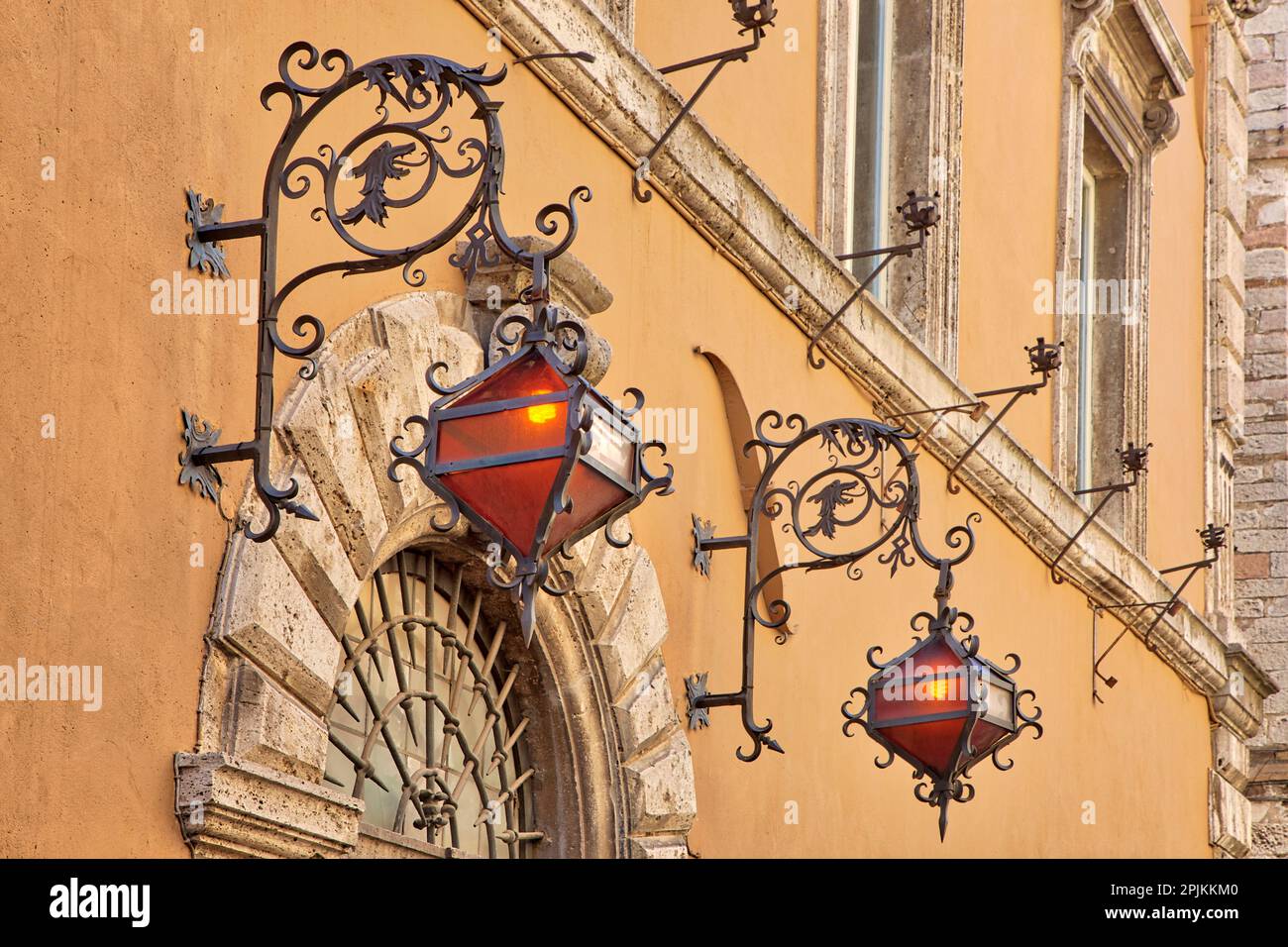 Italy, Umbria, Assisi. Wrought iron dragon lights on a wall above an ...