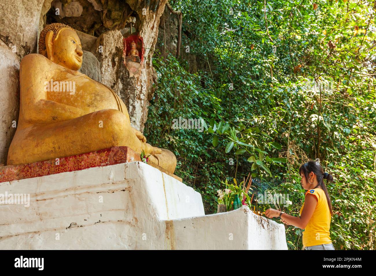 Laos, Luang Prabang. Pak Ou. Tham Ting caves. Young woman offering ...