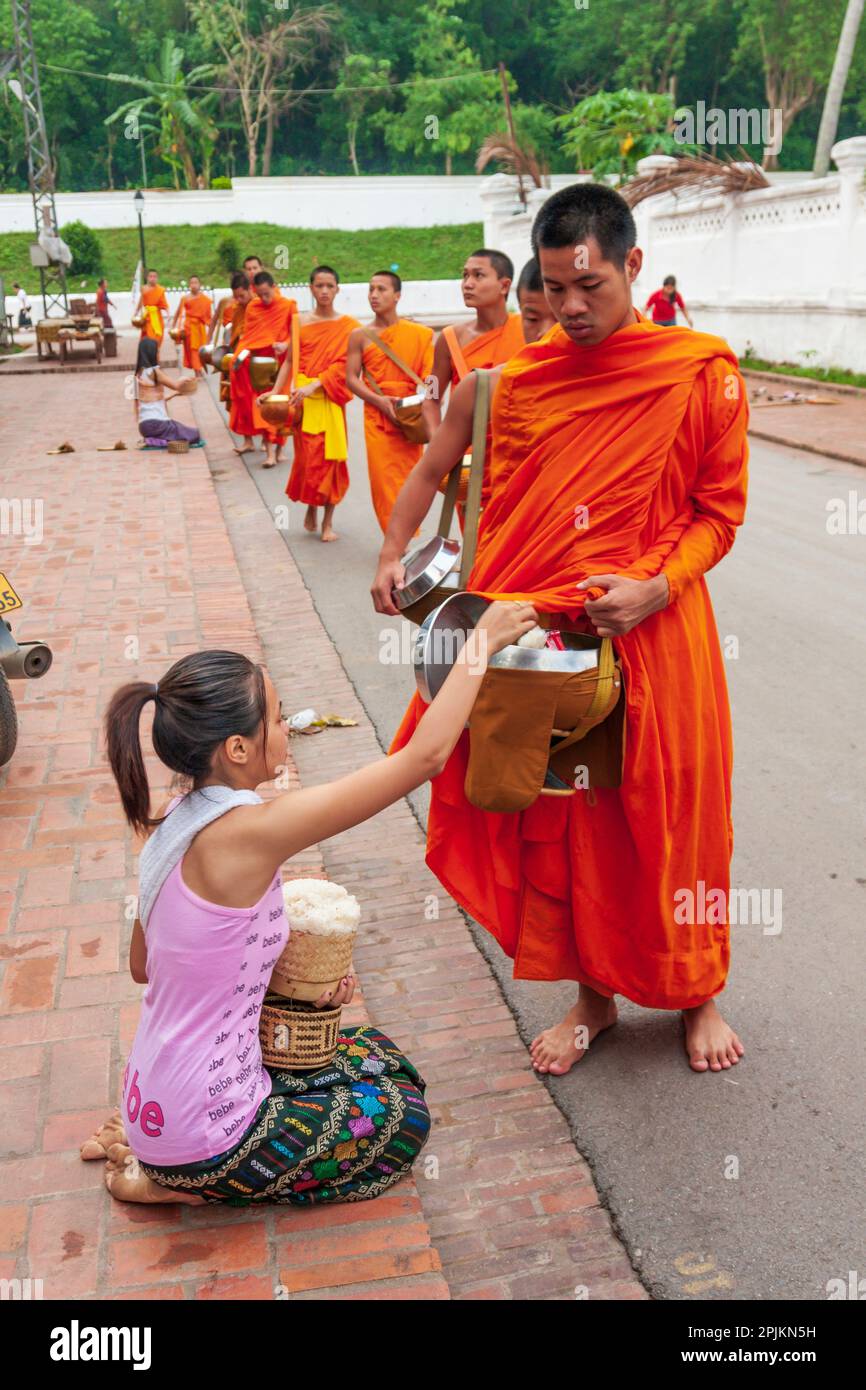 Laos, Luang Prabang. Young woman giving offering to monk. (Editorial ...