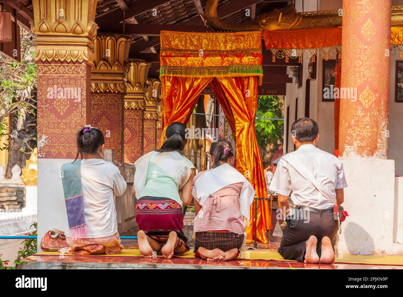 Laos, Luang Prabang. People kneeling in prayer at Wat Sene Souk Haram ...