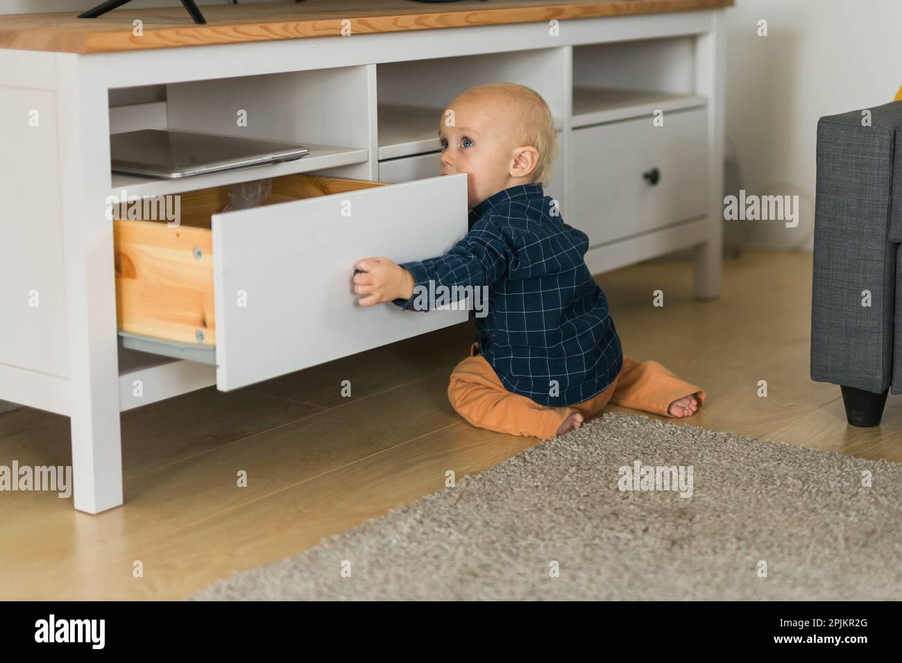 Toddler baby boy open cabinet drawer with his hand. Child explore what ...