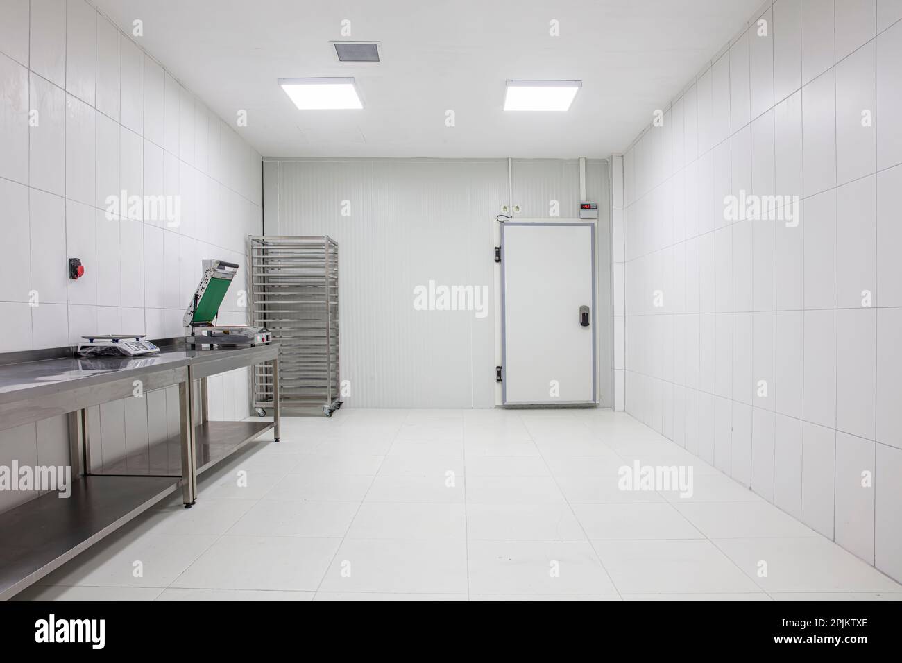 Cold room in warehouse with empty metal shelves. Food packaging machine ...