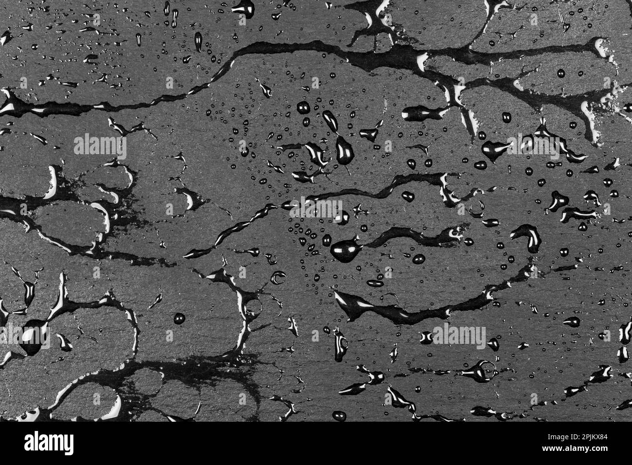 Water drops on dark flat stone surface of basalt or granite background ...