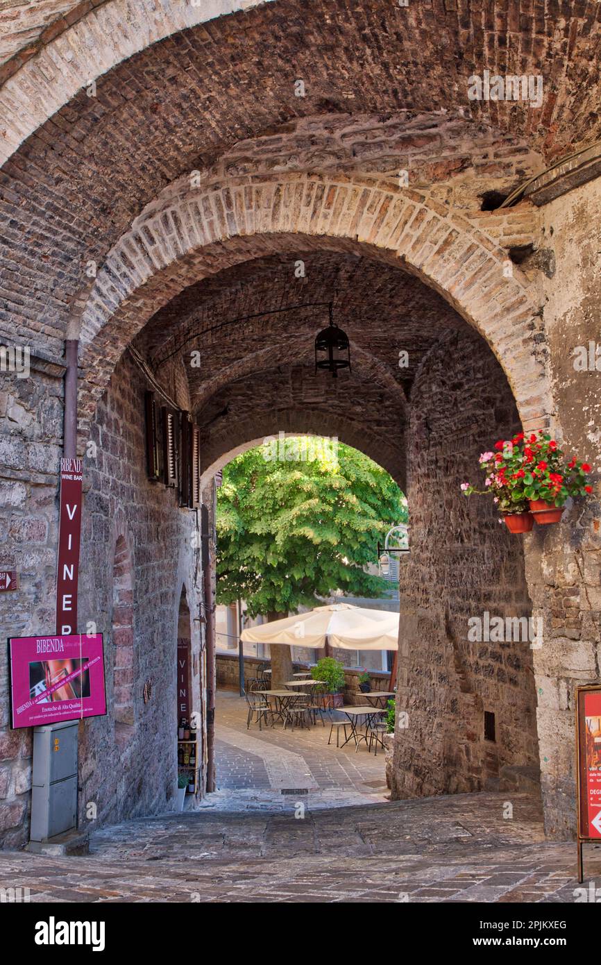 Italy, Umbria, Assisi. Archway leading down to a restaurant with outdoor seating. (Editorial Use ...