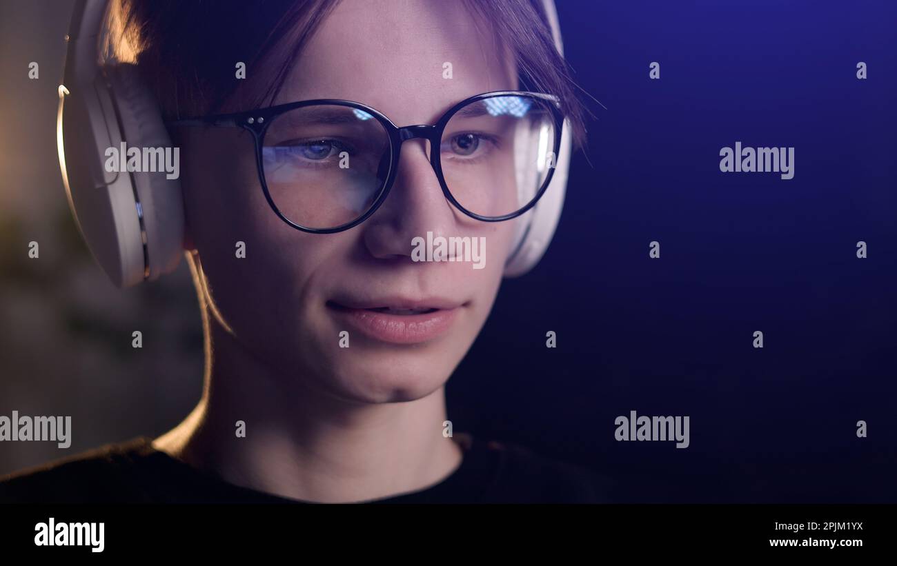 Young gamer man in glasses with screen reflection and headphones ...