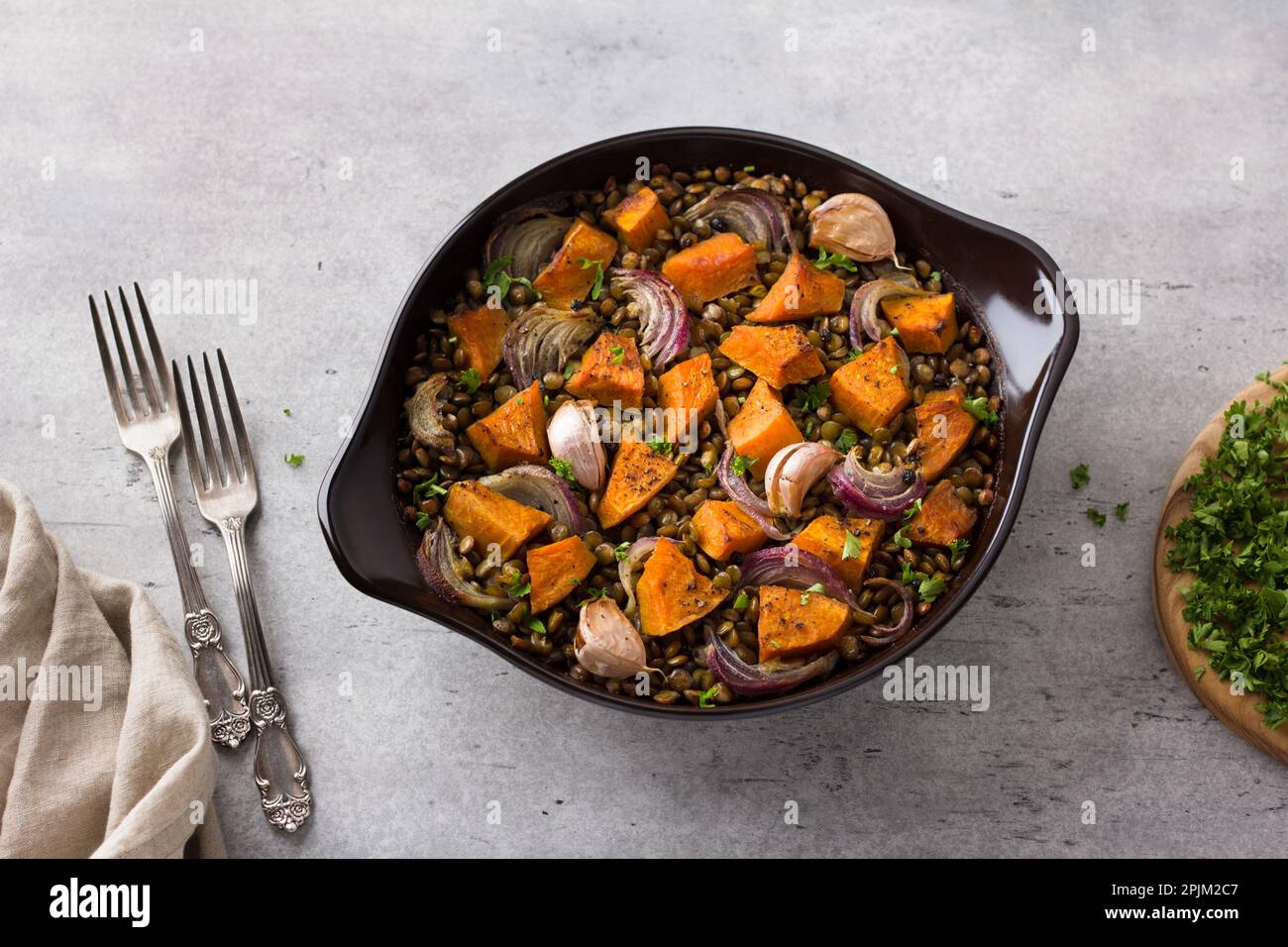 Baked lentils with pumpkin and onions in a ceramic mold on a gray ...