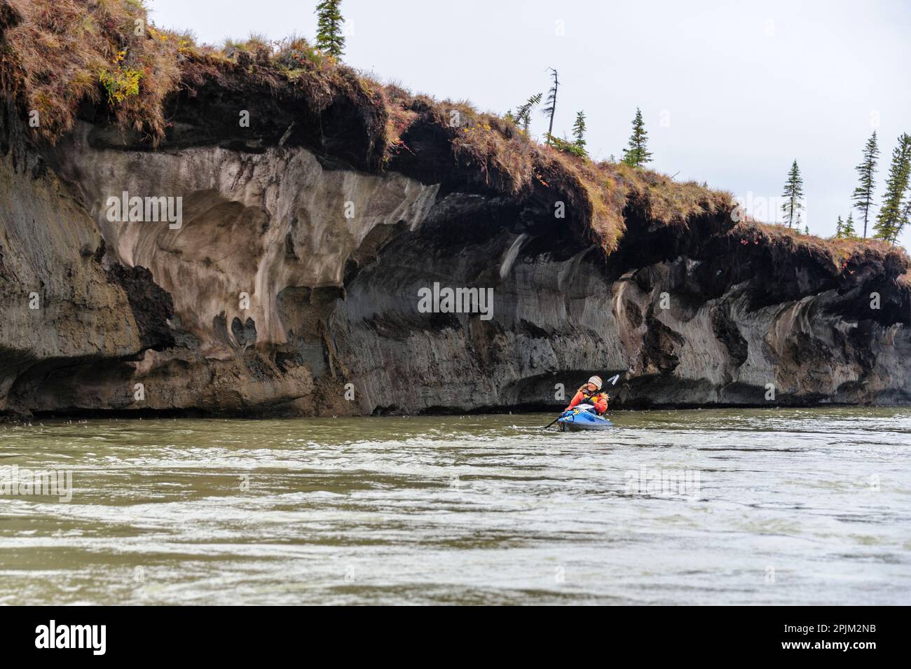 USA, Alaska, Noatak, Noatak River. Paddling along a wall of permafrost ...