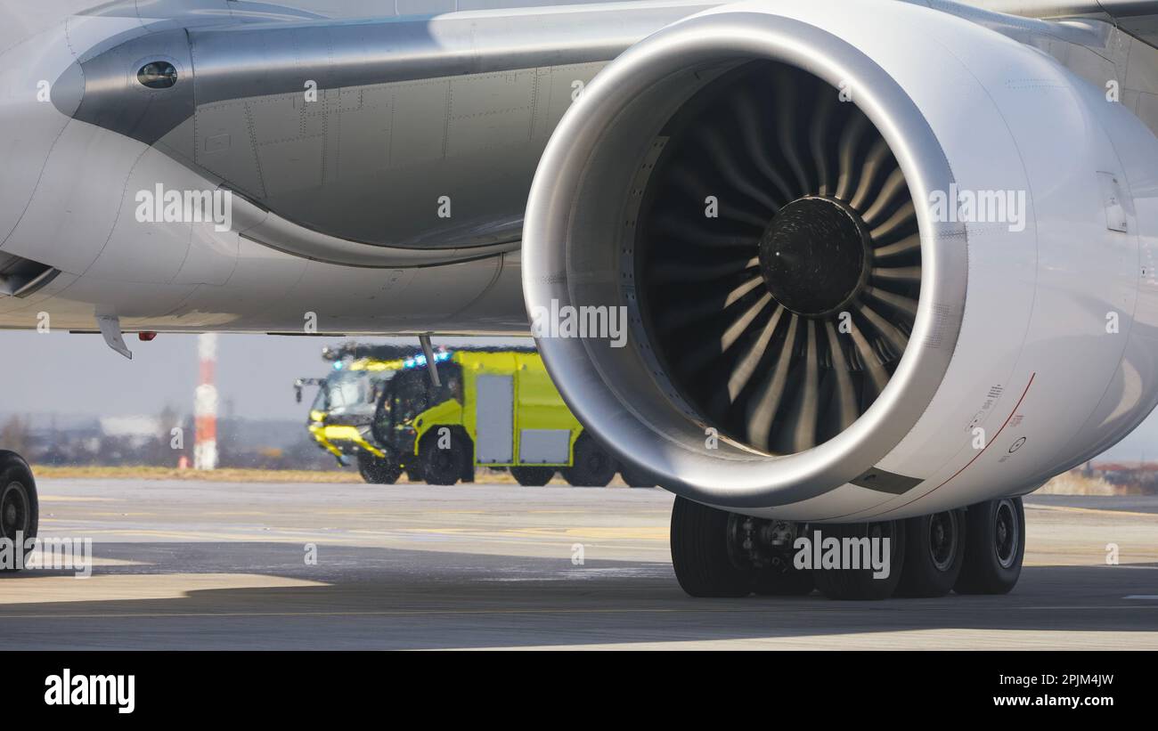 Fire truck of airport rescue and fire brigade behind engine of airplane ...