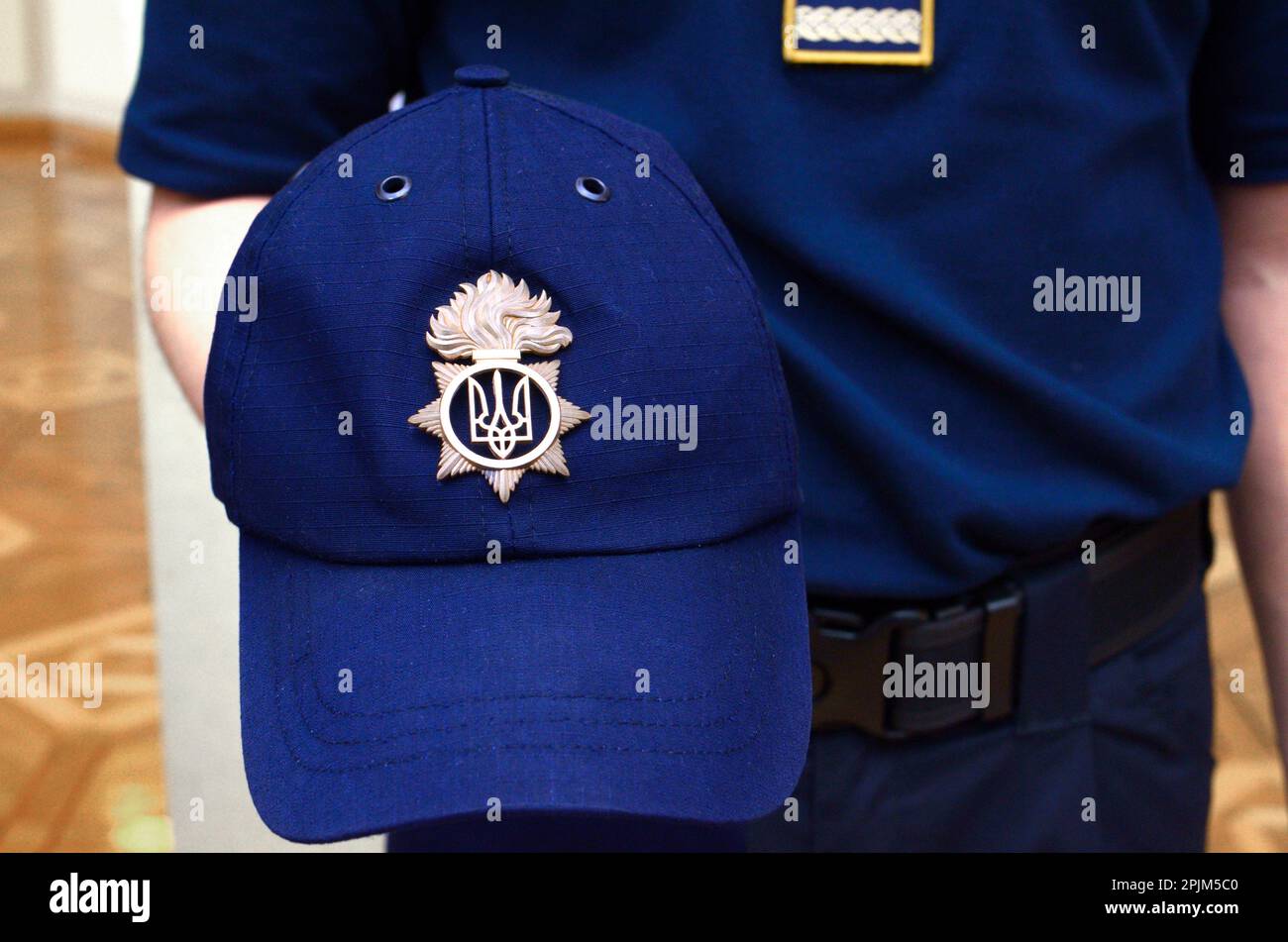 Ukrainian policeman hand holding a blue cap with a coat of arms Tryzub ...