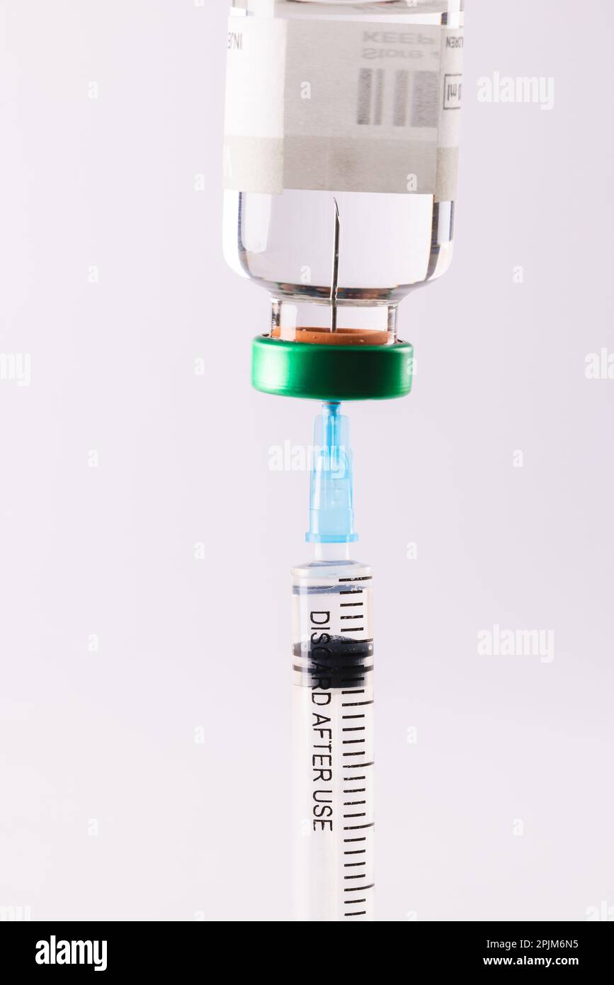 Syringe filling from vial of clear liquid such as insulin, on white ...