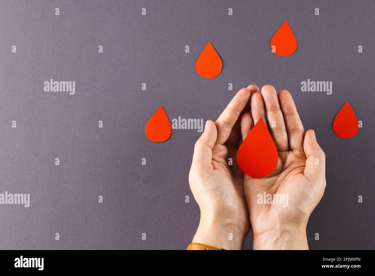Hands of caucasian woman cupping blood drop, with blood drops on grey ...